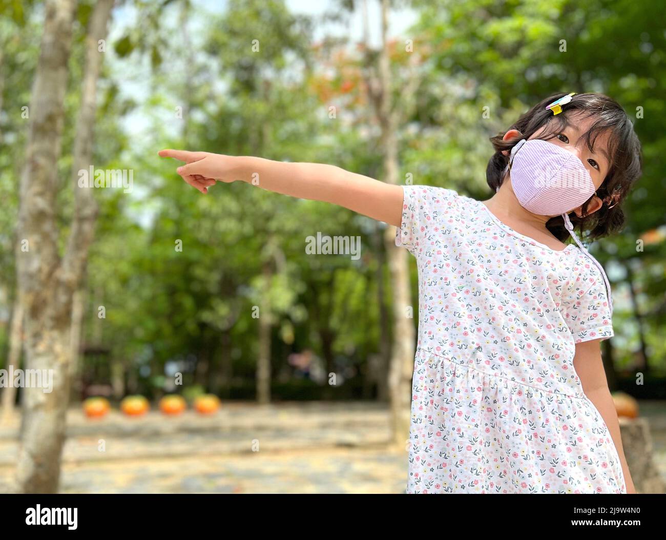 cute little girl wearing masks points in the garden with copy space Stock Photo - Alamy