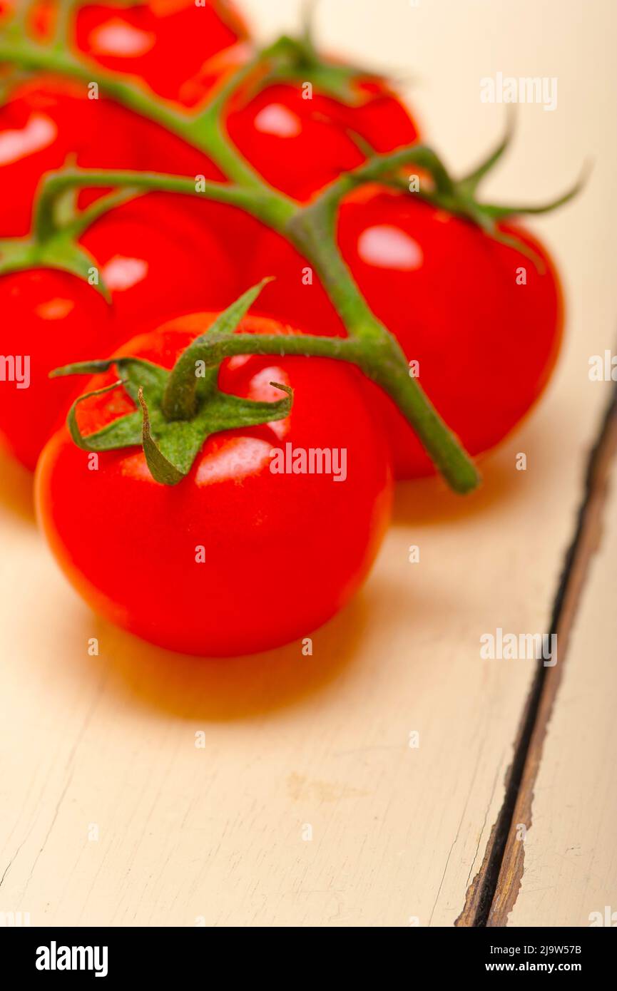 fresh cherry tomatoes on a cluster over rustic wood table Stock Photo ...