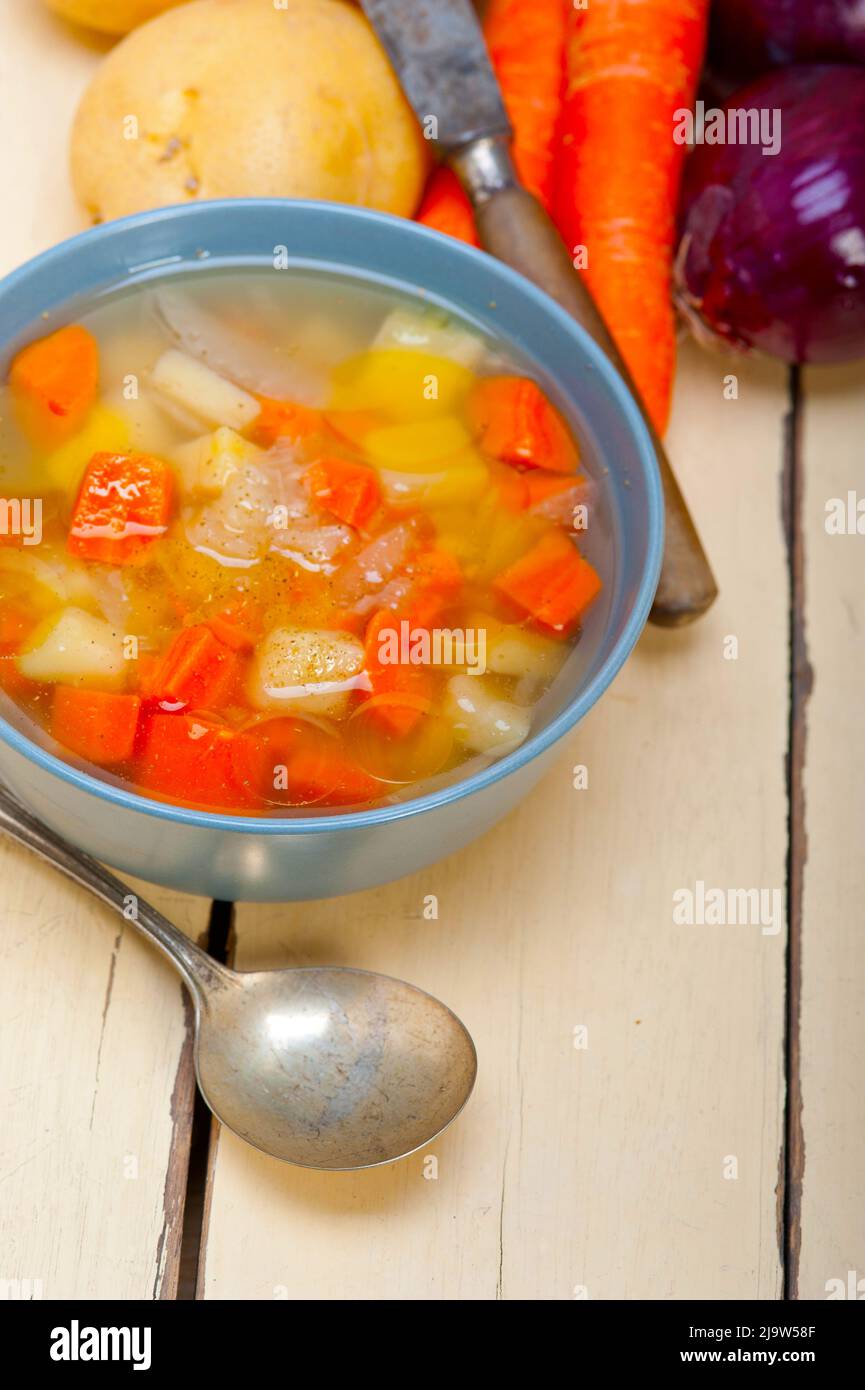 Traditional Italian minestrone soup on a rustic table with ingredients ...