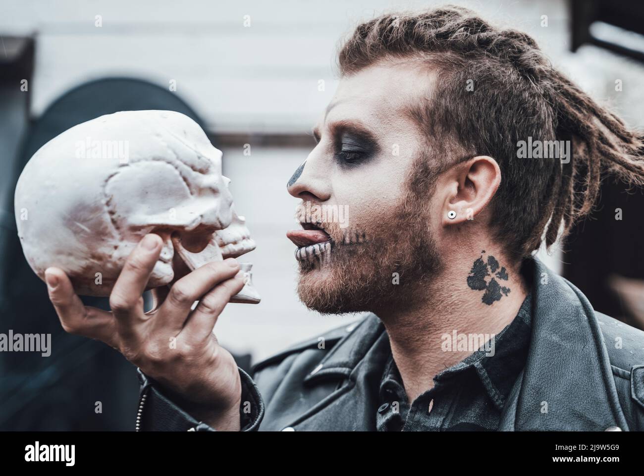 Scary man with dreadlocks looking at skull,showing tongue.Celebrating ...