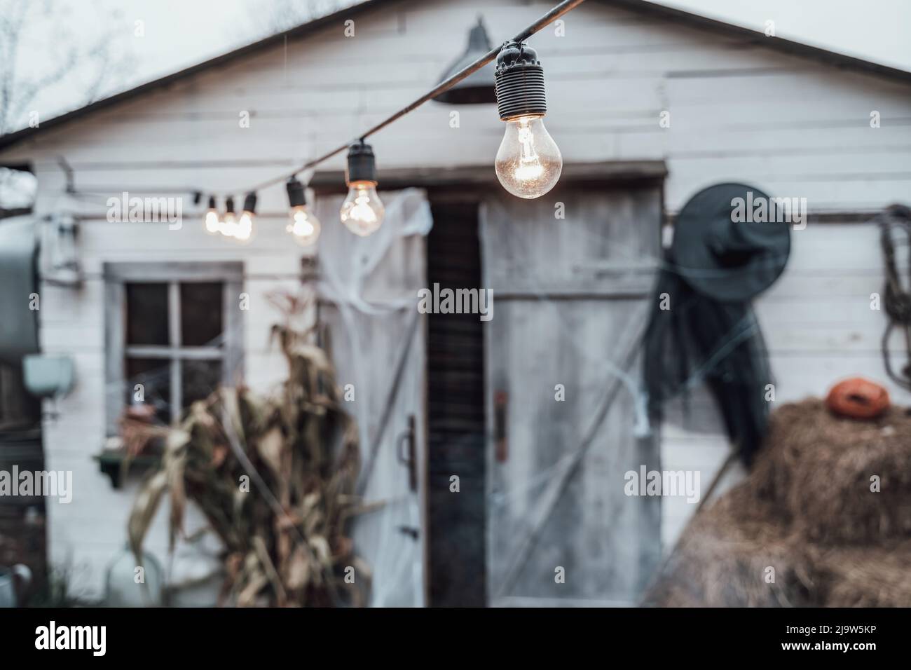 Light bulbs on the garland near old scary decorated barn with hay ...