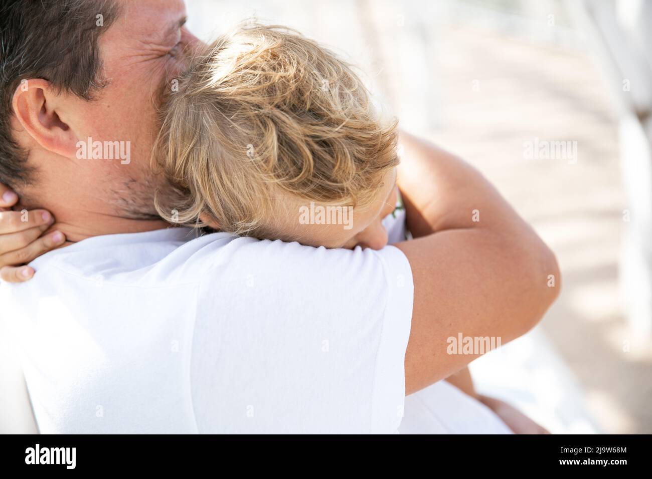 On a warm summer day, a Caucasian man gently and lovingly hugs his ...