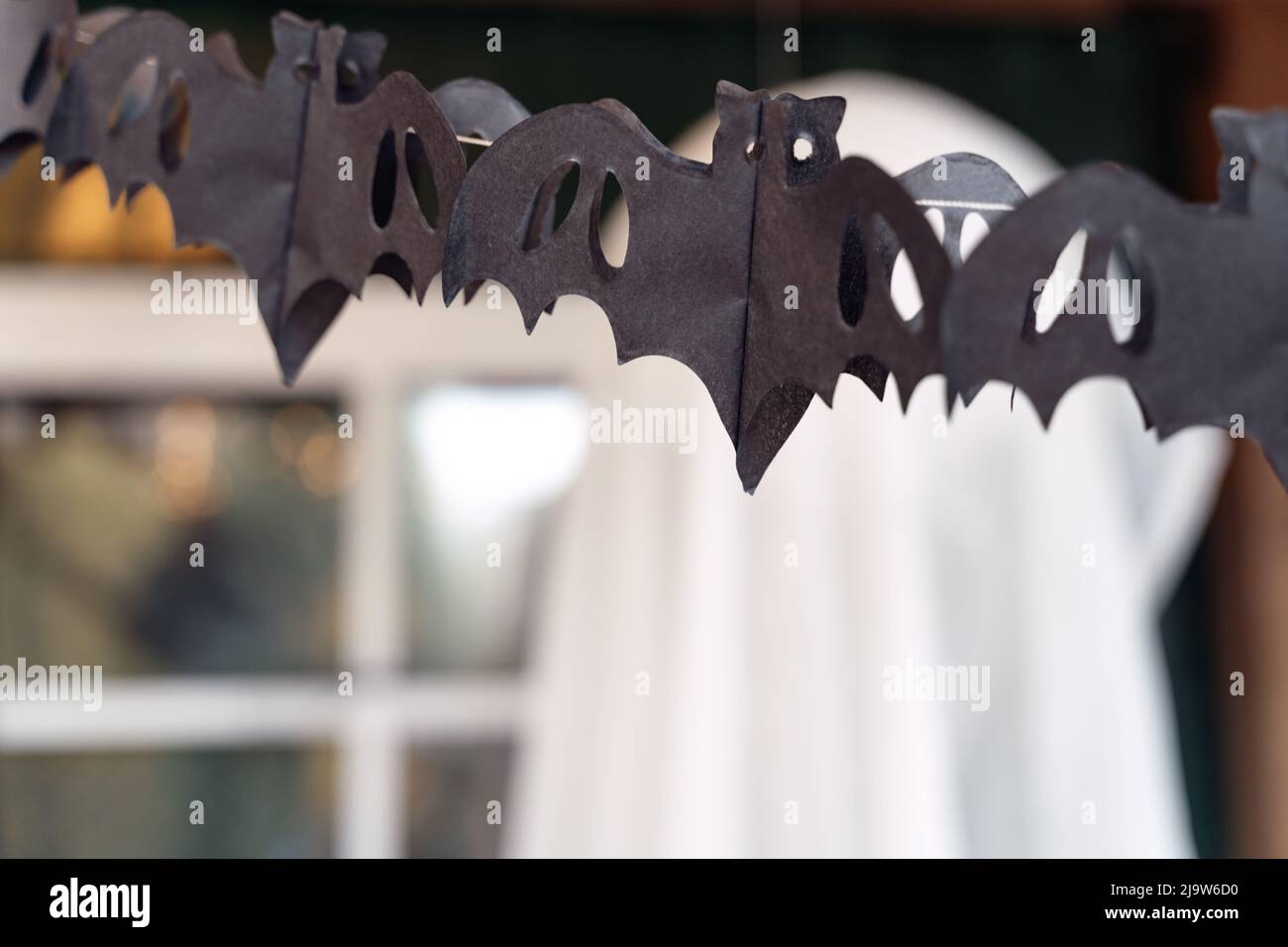 Black paper cut out garland in shape of flying bats.Burning lantern ...