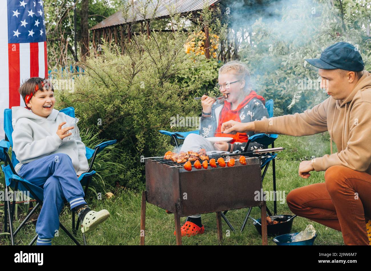 Happy young family make barbecue together in garden. People barbecuing ...