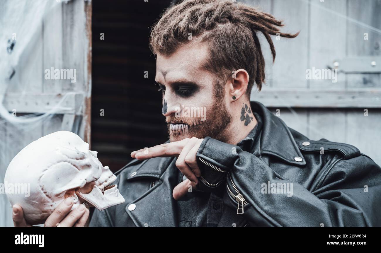 Scary man with dreadlocks looking at skull. Celebrating halloween ...