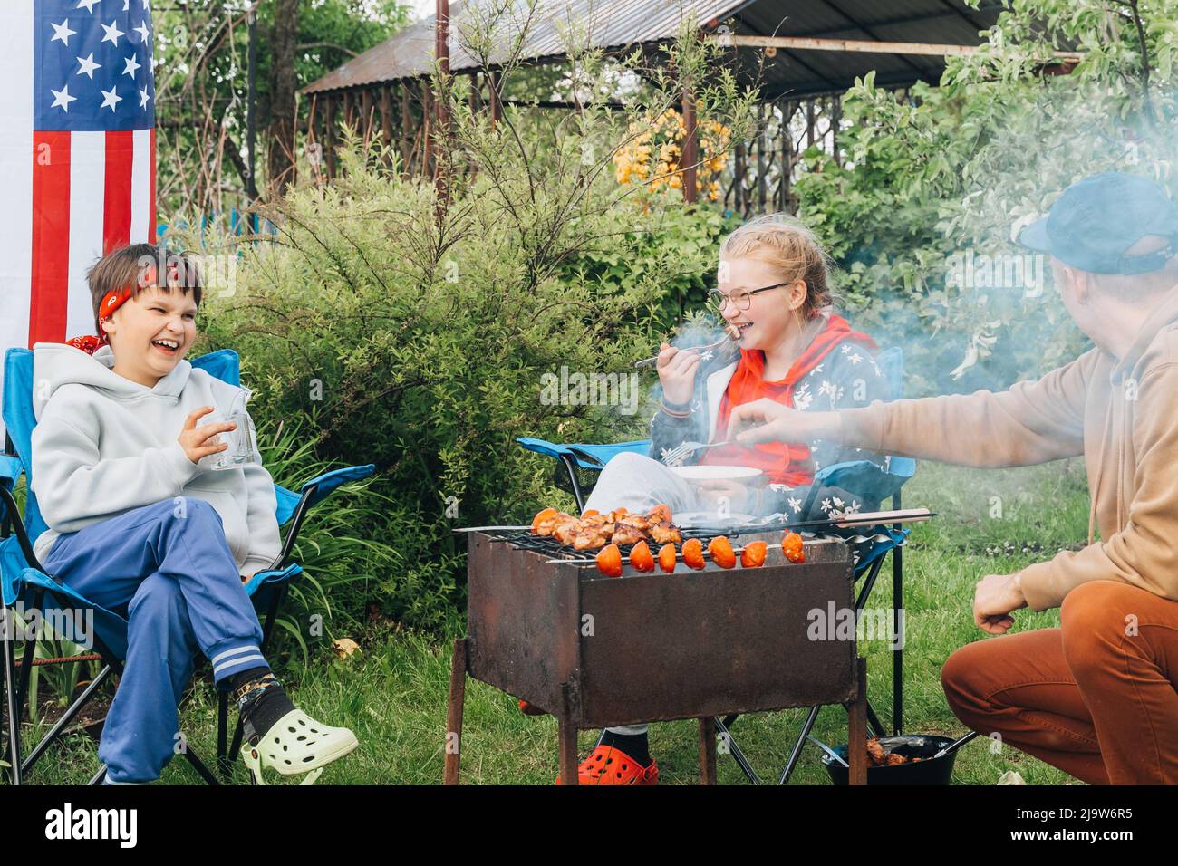 Happy young family make barbecue together in garden. People barbecuing ...