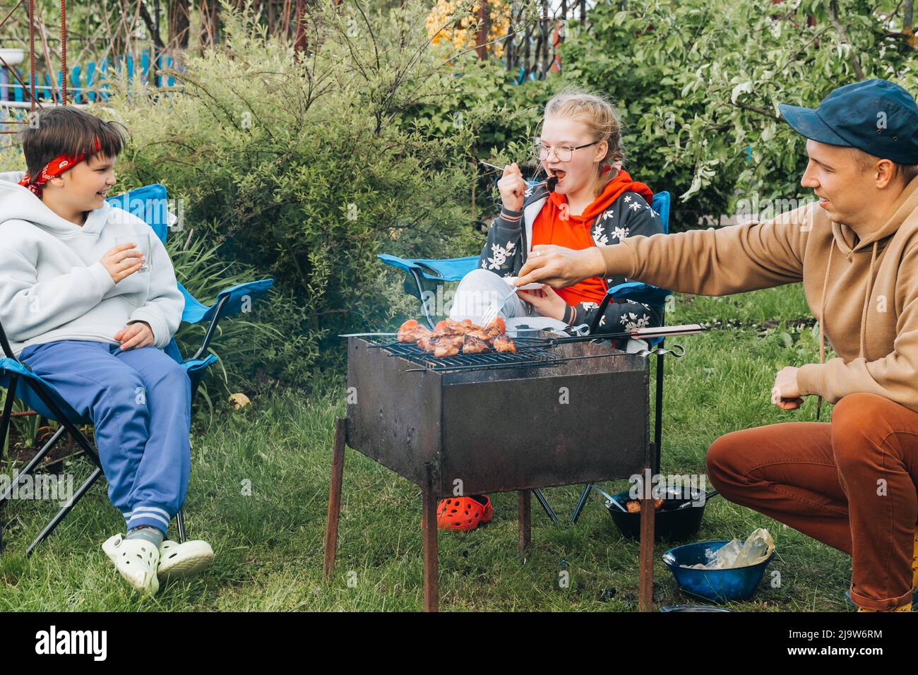 Happy young family make barbecue together in garden. People barbecuing ...
