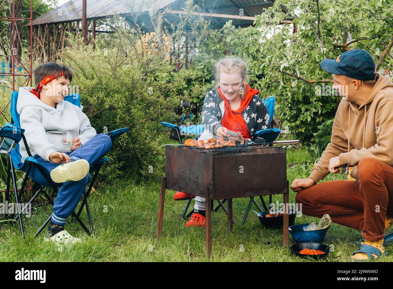 Happy young family make barbecue together in garden. People barbecuing ...