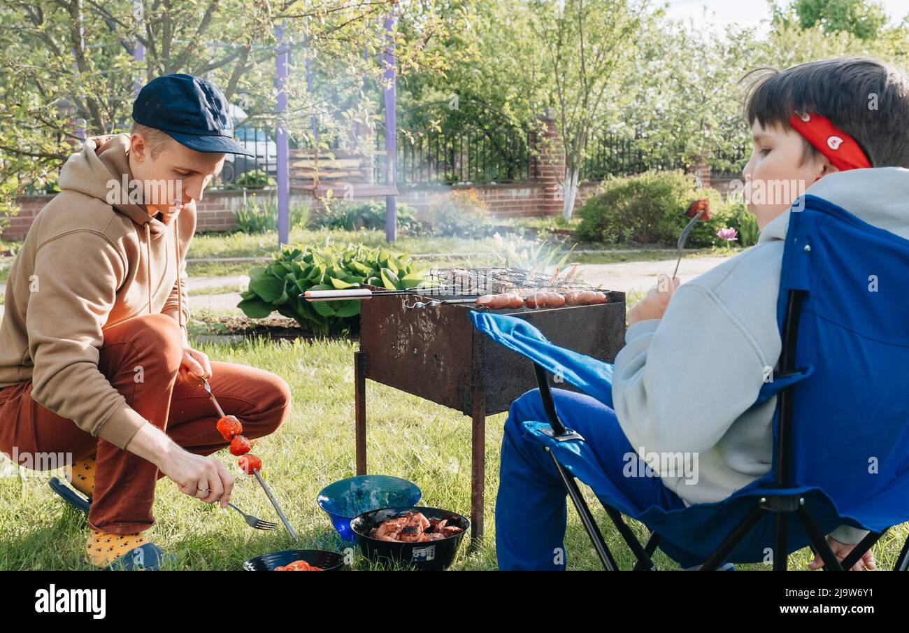 Happy young family make barbecue together in garden. People barbecuing ...