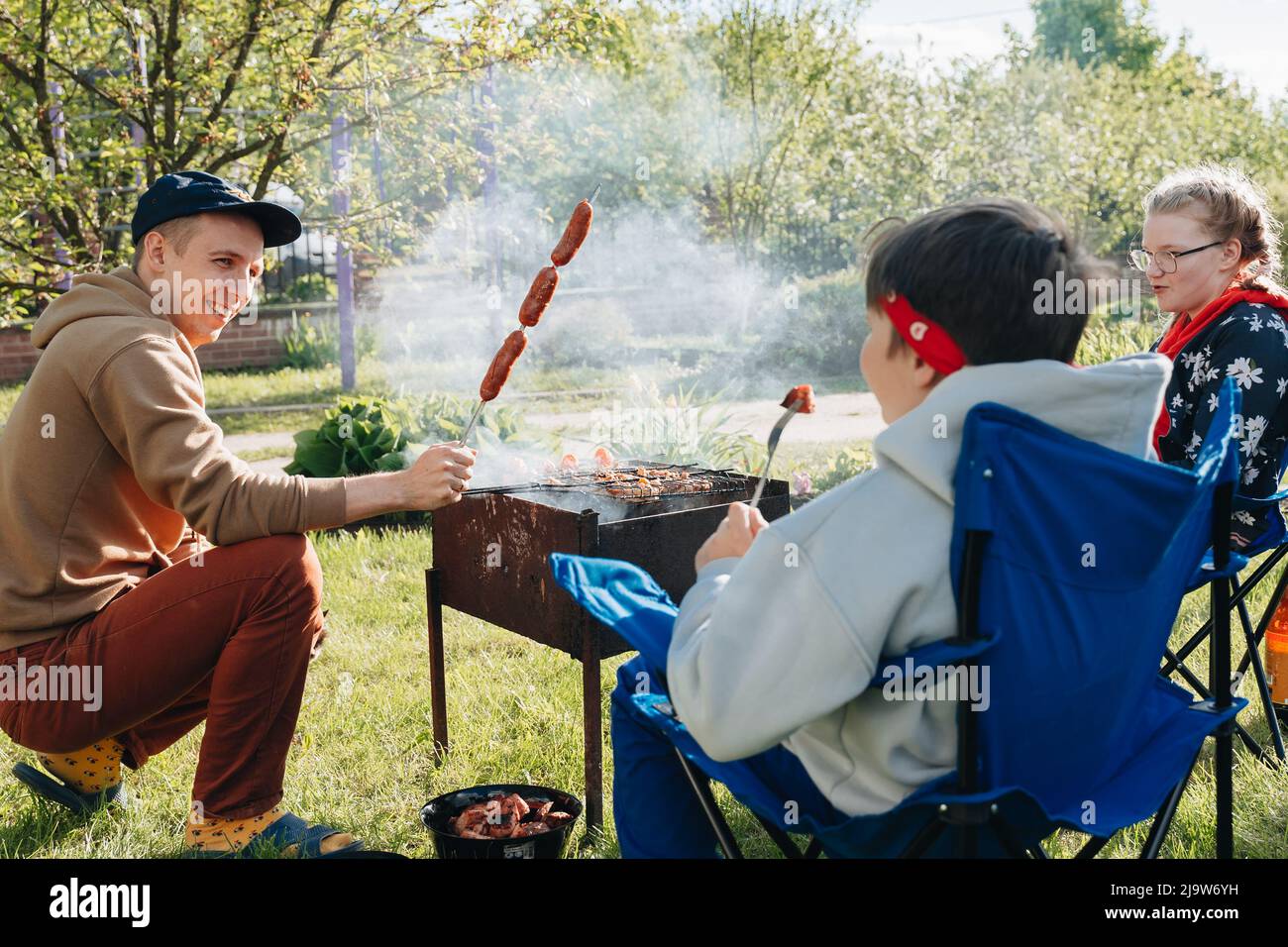 Happy young family make barbecue together in garden. People barbecuing ...