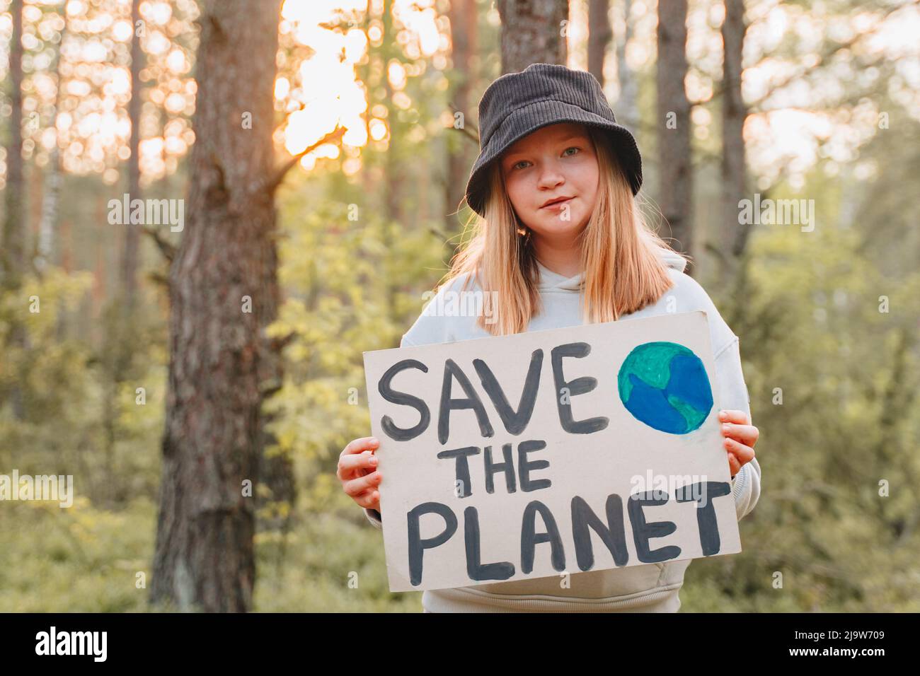 happy smiling teen looking to camera holding a colorful save planet ...