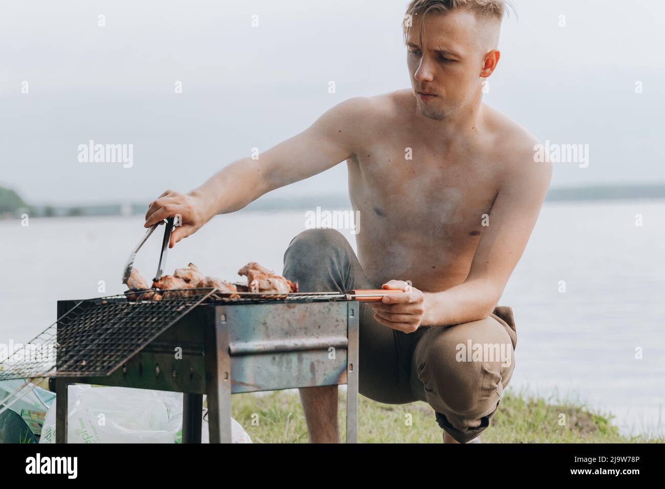 portrait of Smiling man seasoning meat on grill. Handsome man preparing ...