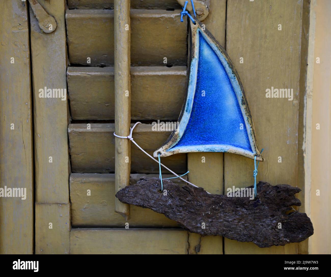 Traditional handmade glazed ceramic sailing boat hanging on an antique ...