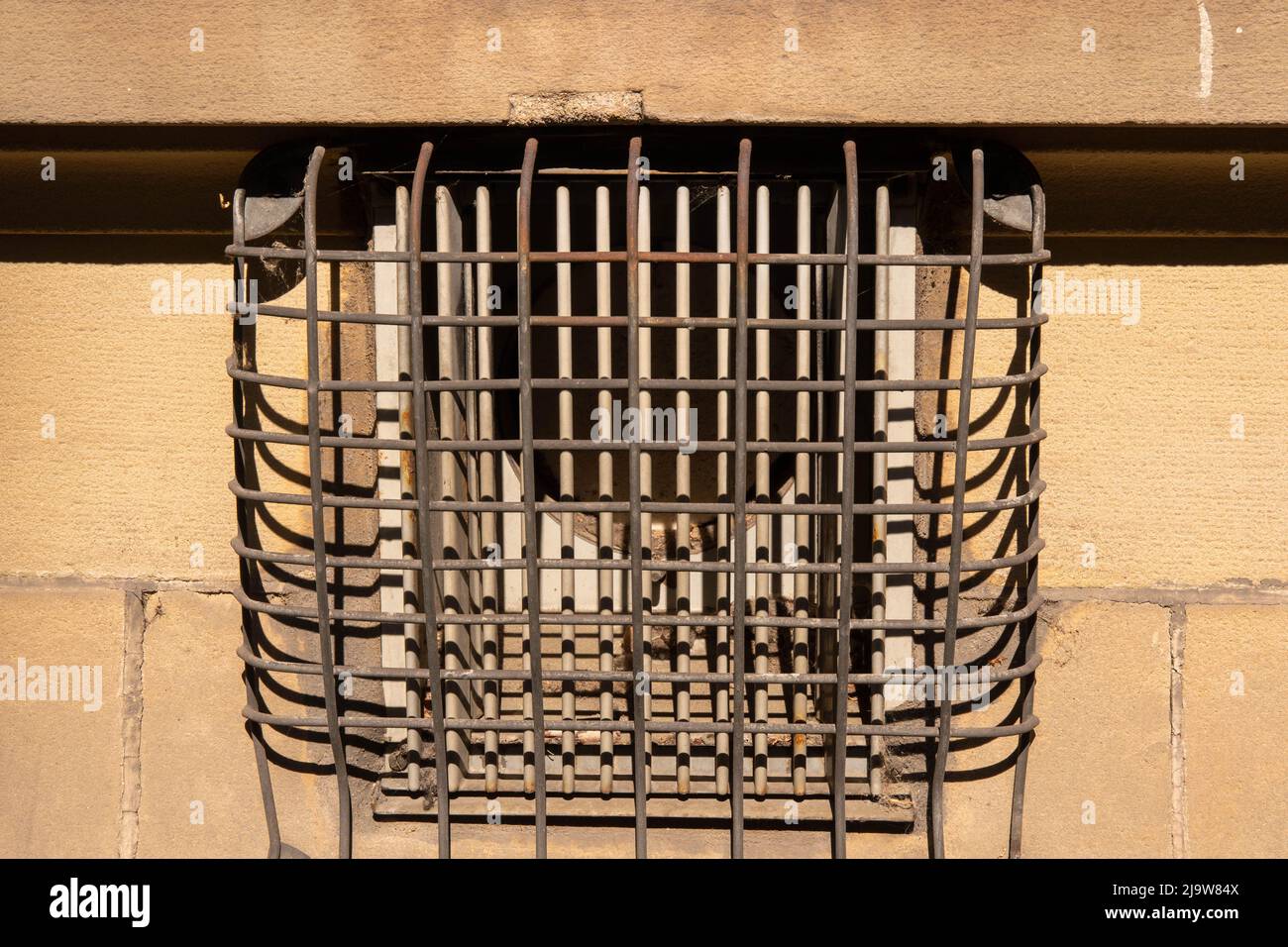 old ventilation system with protective grille on the wall of the house ...