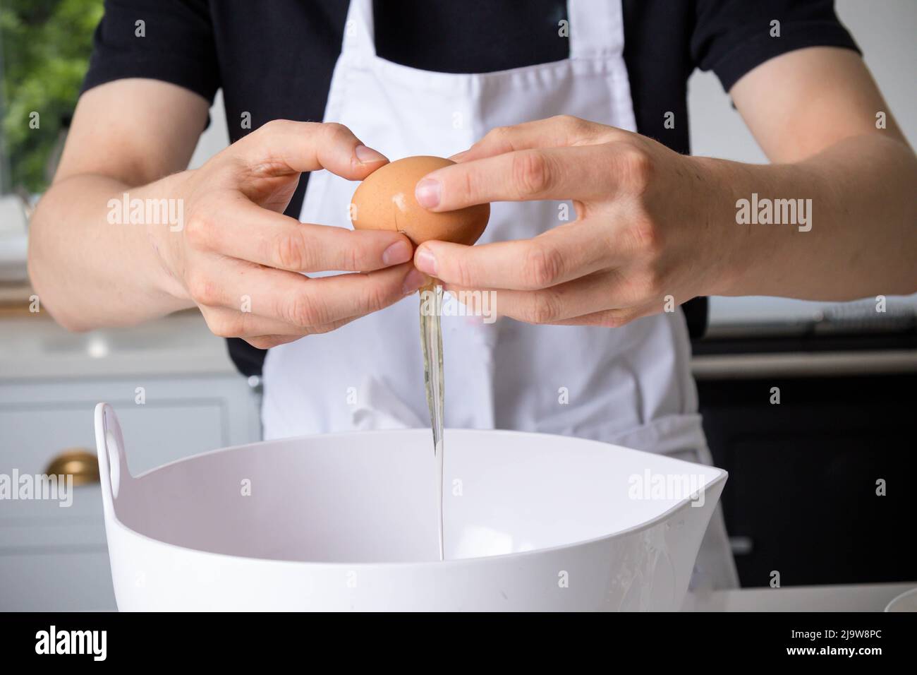 A teenage boy in a domestic kitchen cracking an egg Stock Photo - Alamy