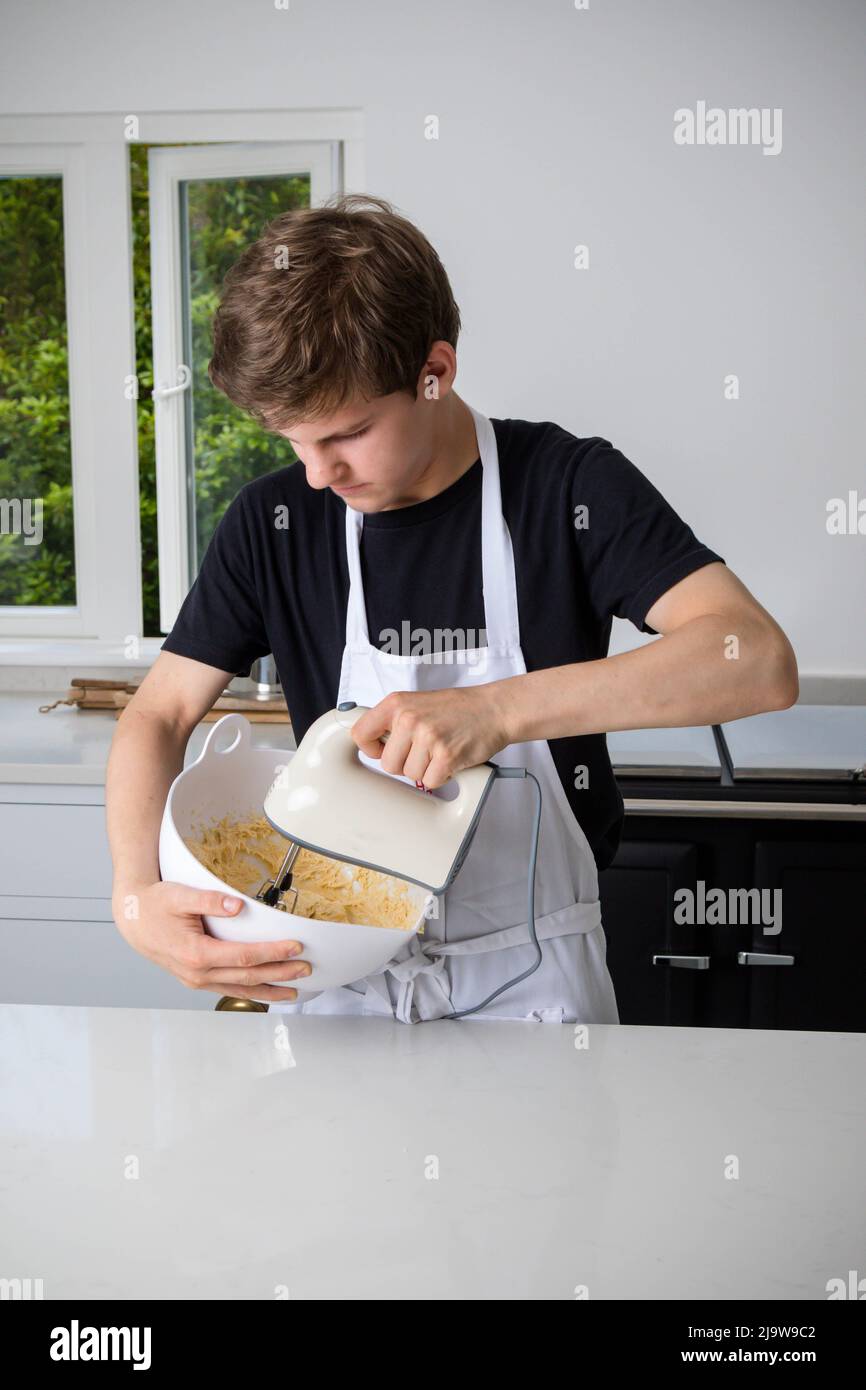 A teenage boy in a domestic kitchen using an electric mixer Stock Photo ...