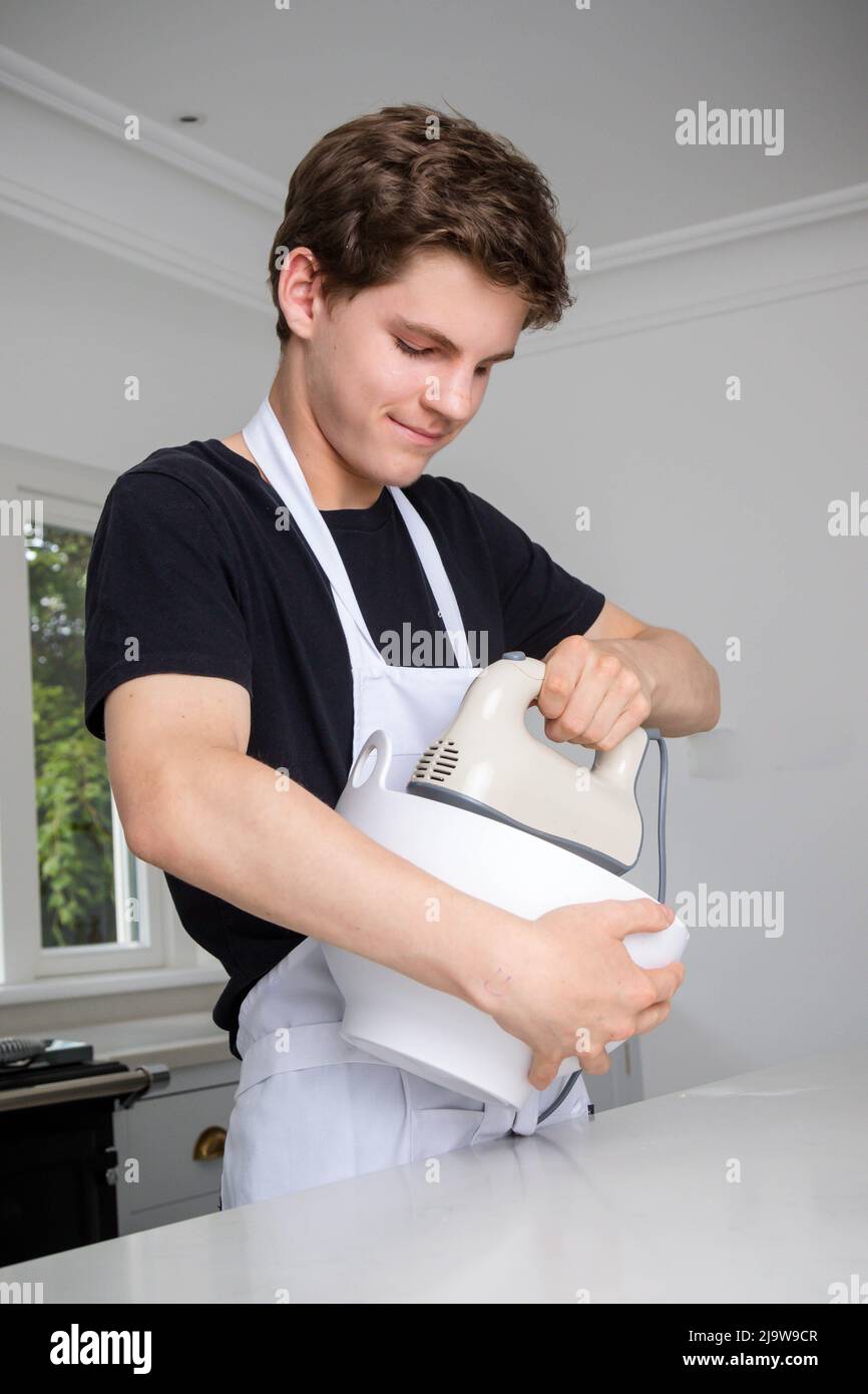 A teenage boy in a domestic kitchen using an electric mixer Stock Photo ...