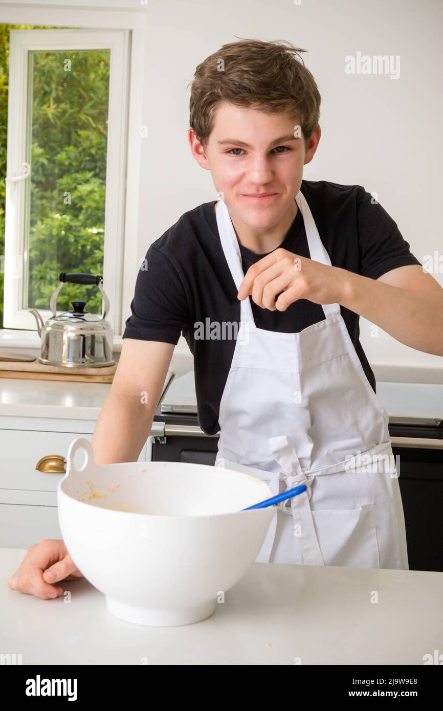 A teenage boy in a domestic kitchen tasting mixed ingredients Stock ...
