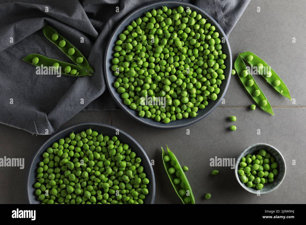 Fresh green peas in plates on a gray background Stock Photo - Alamy