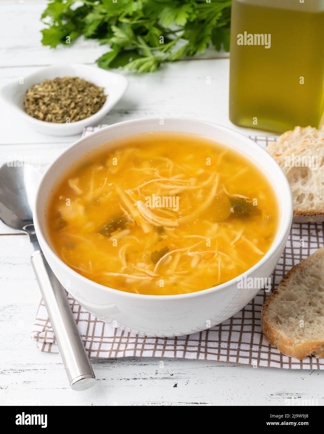 Chicken soup in a bowl with bread slices and seasoning over wooden ...