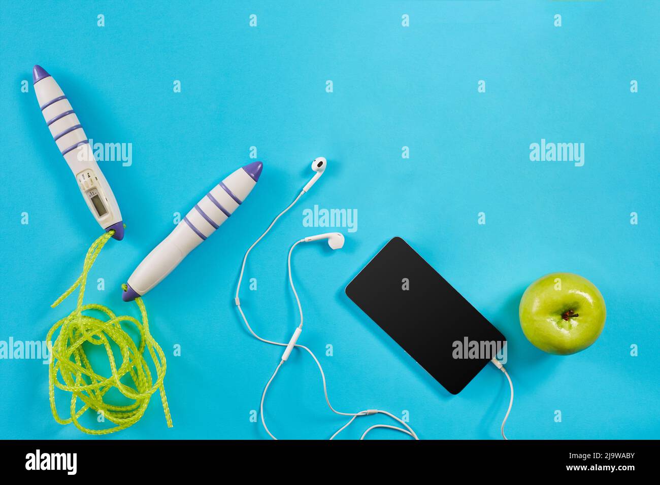 Flat lay shot of Sport equipment. Apple, jump rope, earphones and phone ...