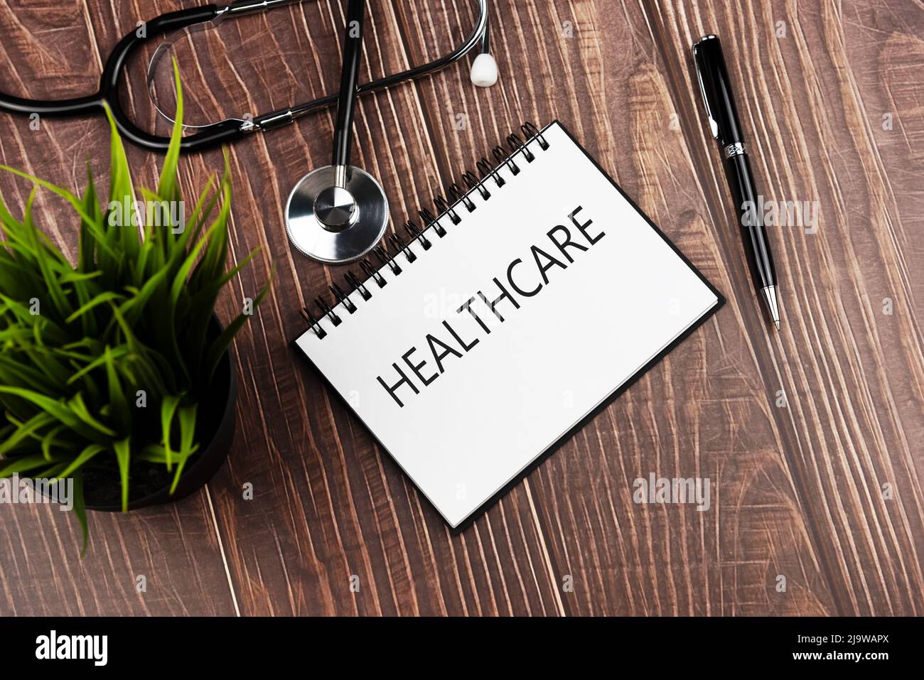 Healthcare text on note pad with stethoscope, pen and green potted ...