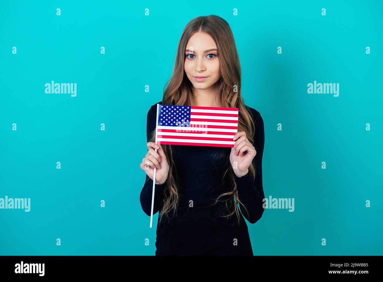 attractive female person holding an American flag in her hand on a blue ...