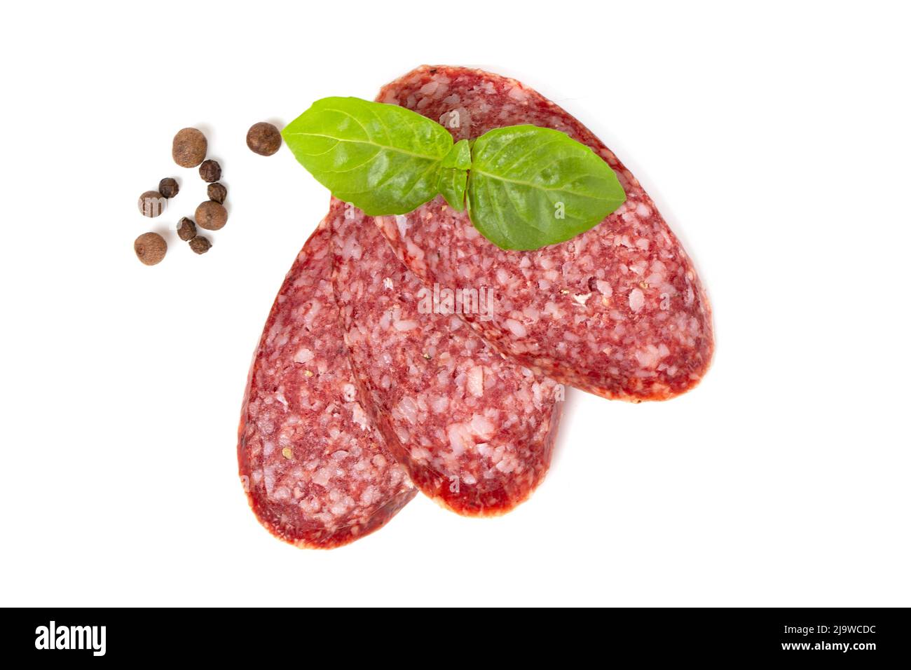 Beef Dried smoked Salami sausage sliced with basil leaf and pepper peas close-up, isolated on a ...