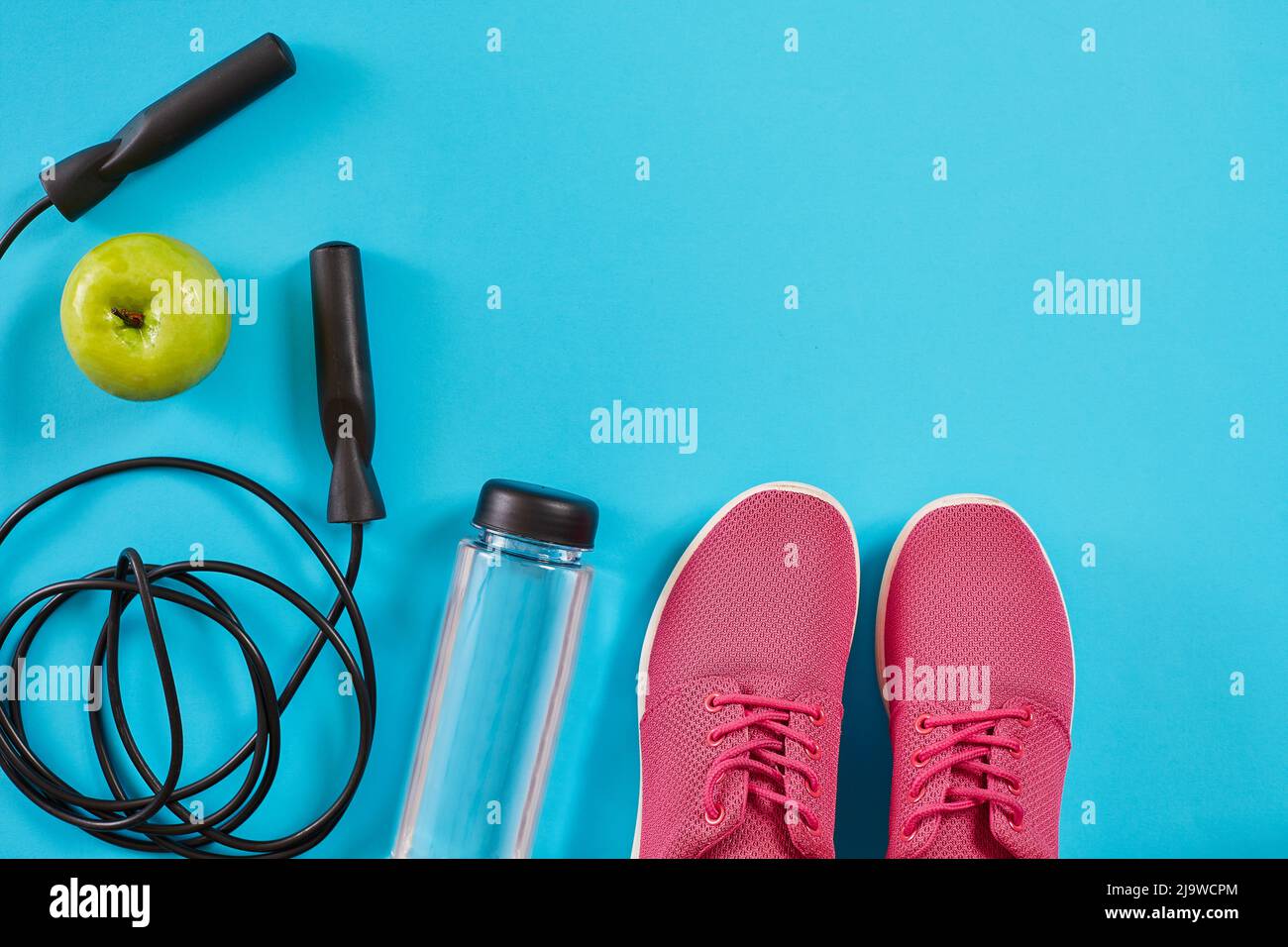 Flat lay of female sport equipments, jump rope, bottle of water and ...