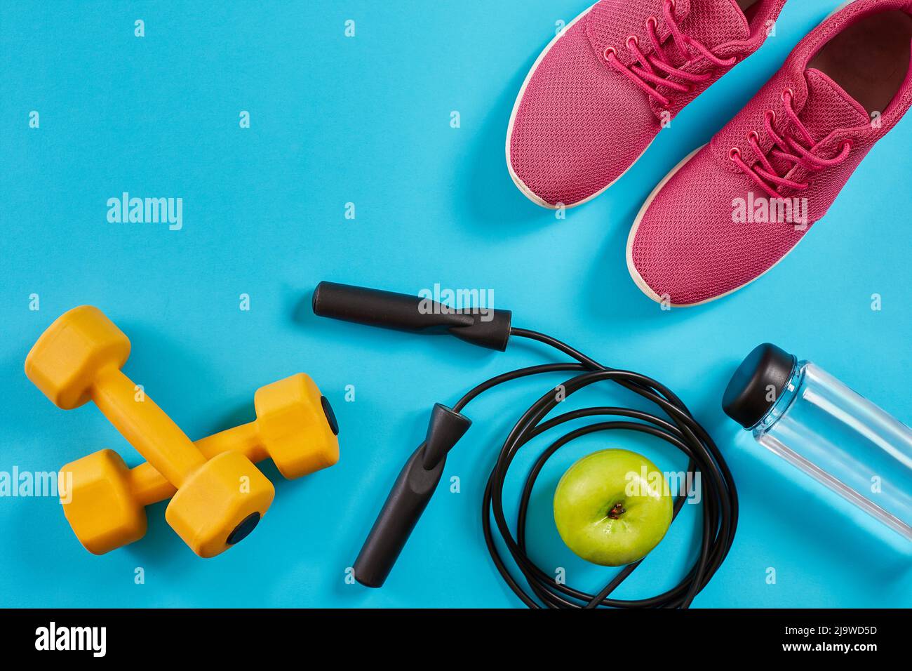 Flat lay of female sport equipments, jump rope, bottle of water and ...