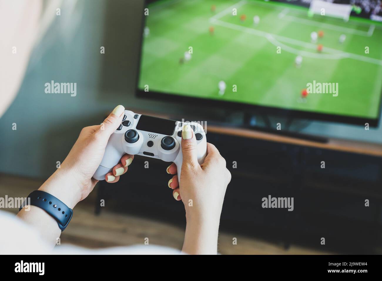 Girl playing a video game console. Game is football. Joystick in hands ...