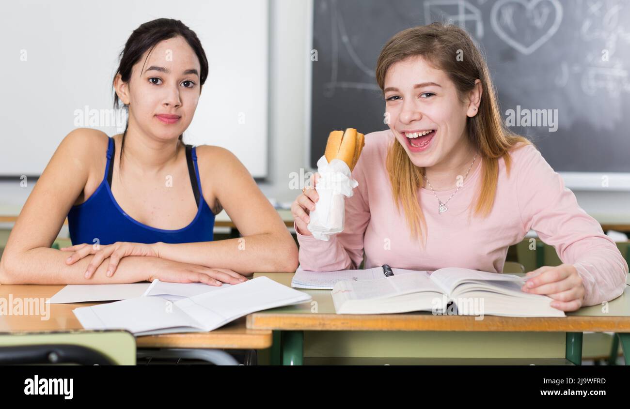 Young girls are eating lunch at the desk and reading text in the ...