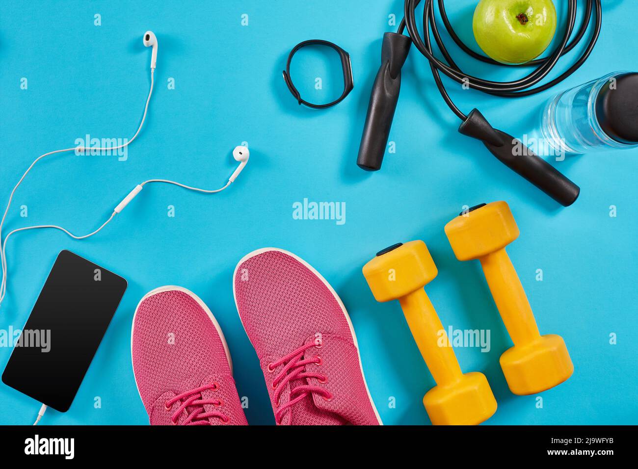 Flat lay shot of sneakers, jumping rope, dumbbells and smartphone on ...