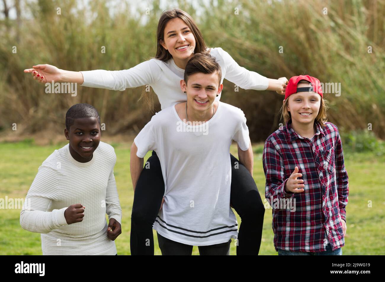 Portrait of positive friends running on field Stock Photo - Alamy