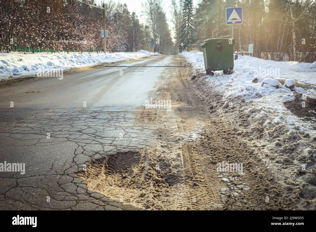 Large pit on the old country road in winter. Mud and snow. Outdoors ...