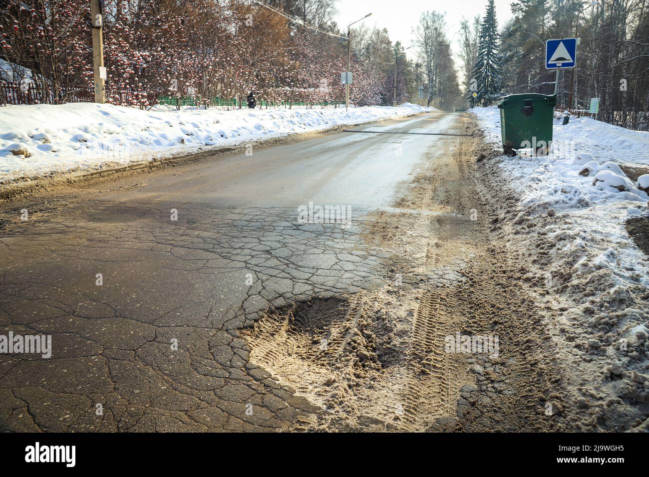 Large pit on the old country road in winter. Mud and snow. Outdoors ...