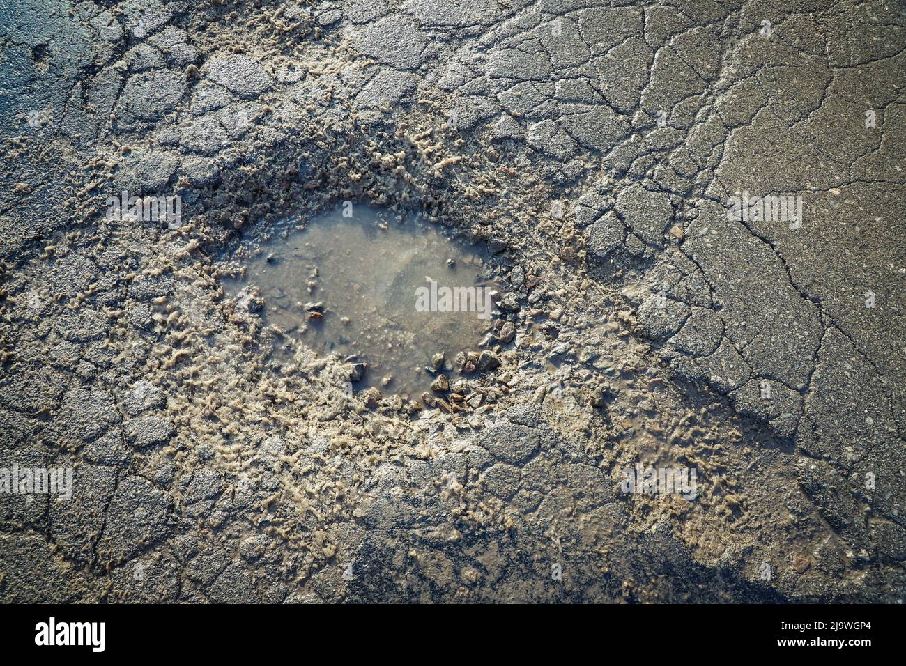 Large pit on the old country road in winter close-up. Mud and snow ...