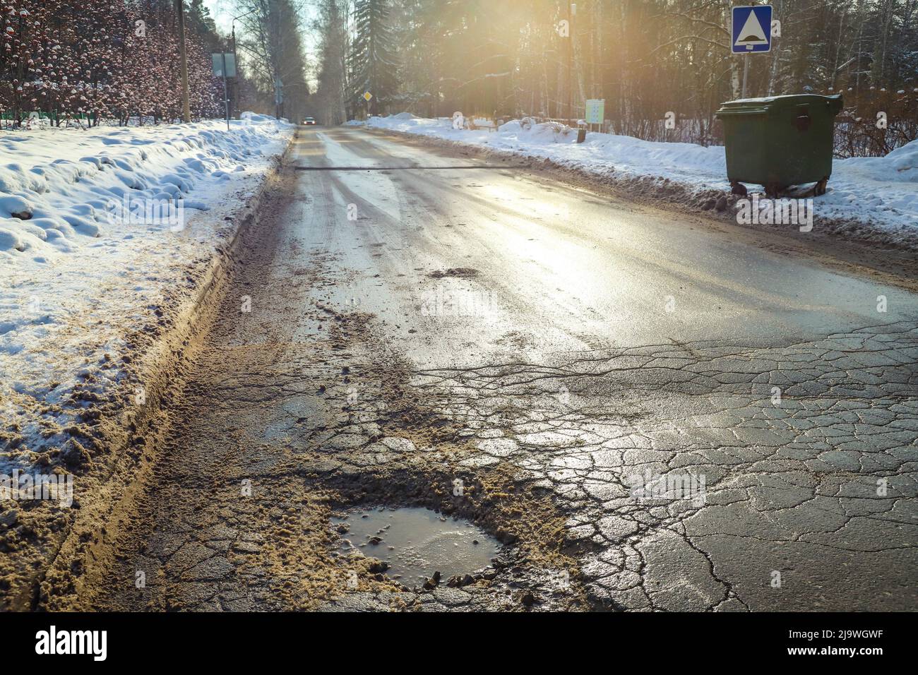 Large pit on the old country road in winter. Mud and snow. Outdoors ...