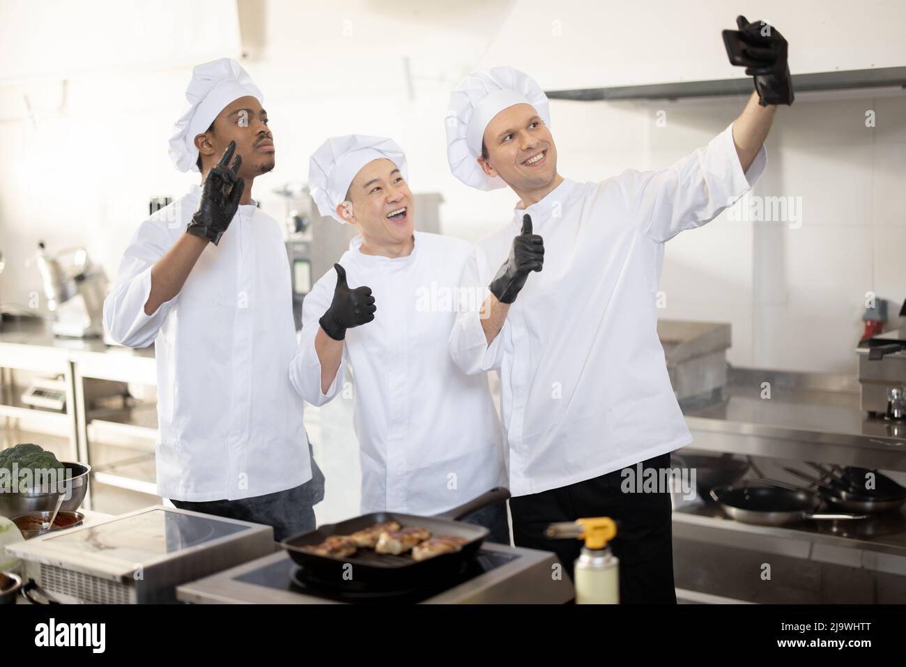 Happy multiracial team of cooks take selfie photo on phone while ...