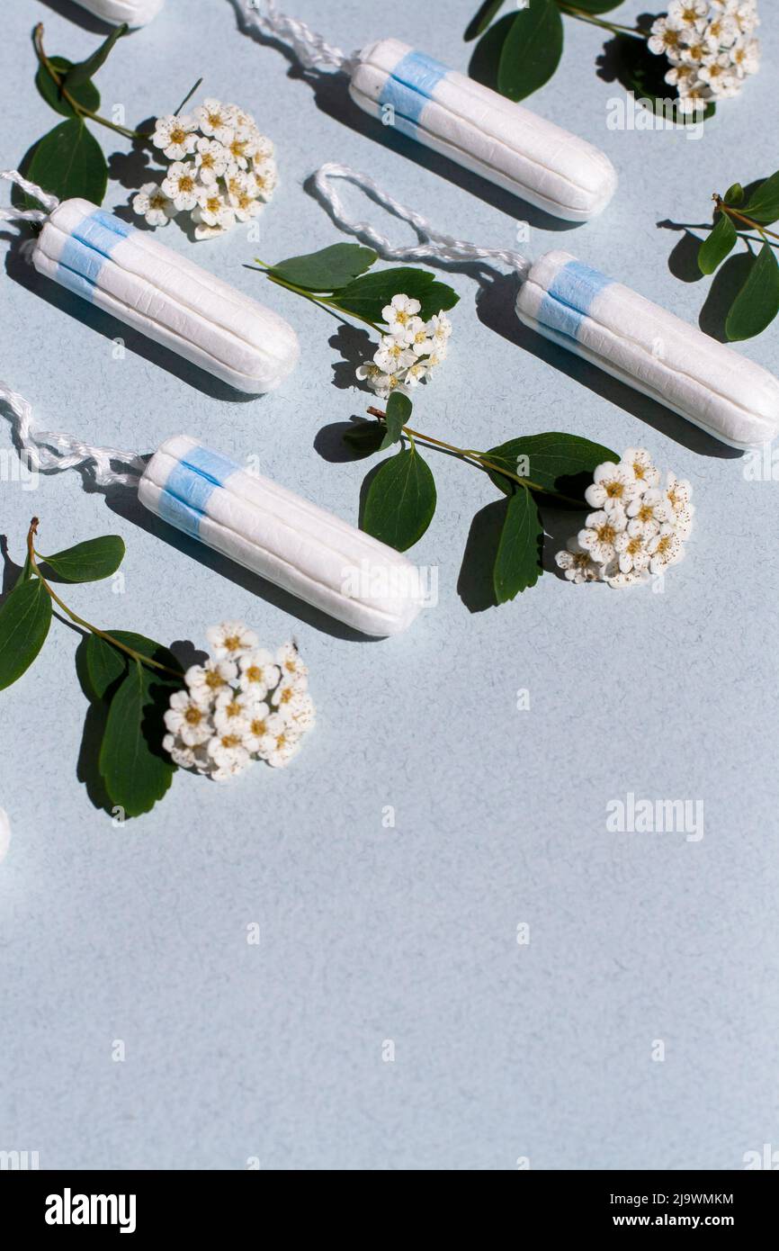 Medical female tampon and white flowers on a blue background. Hygienic ...