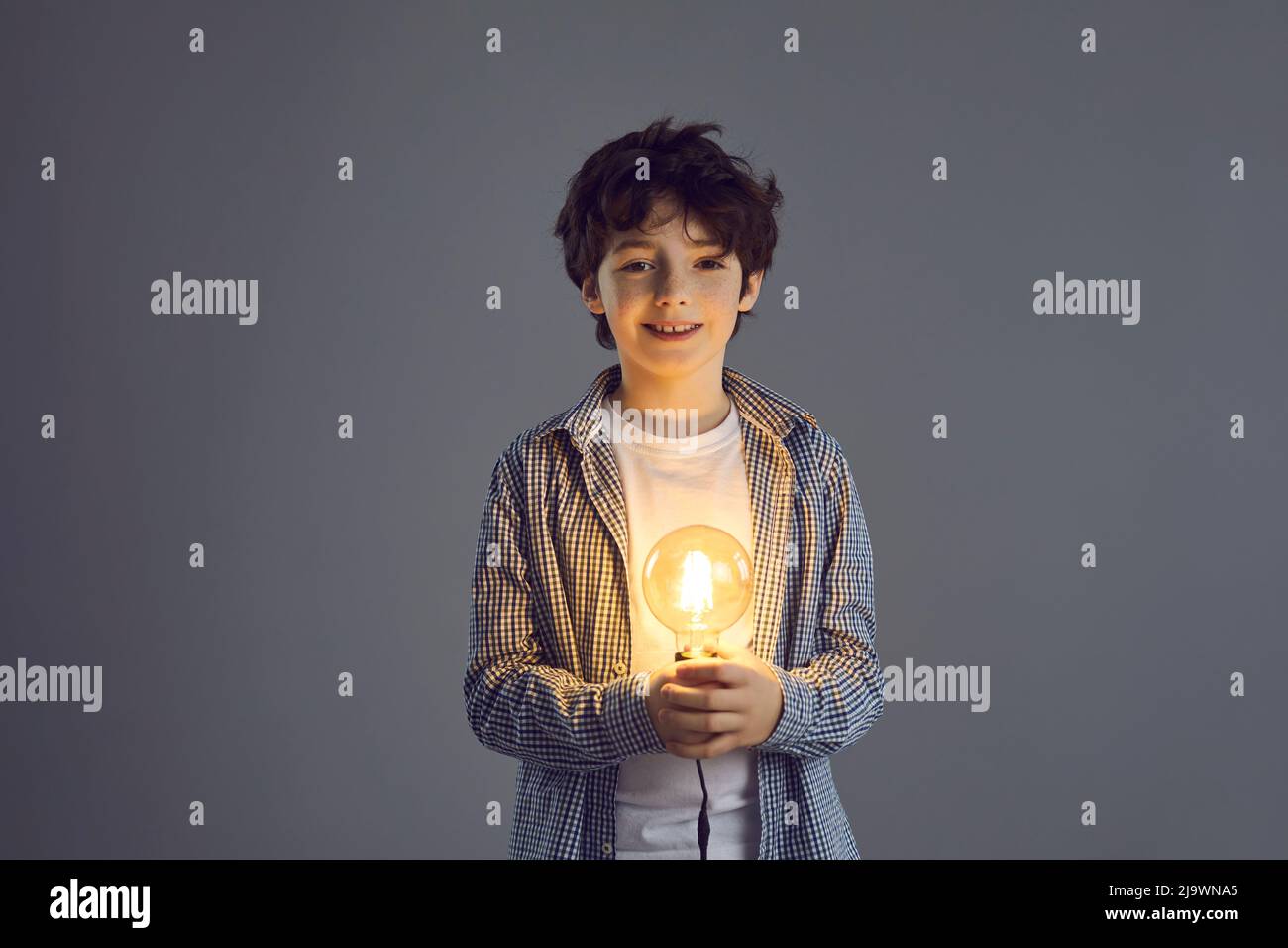 Happy smiling boy schoolchild holding glowing electric light bulb ...