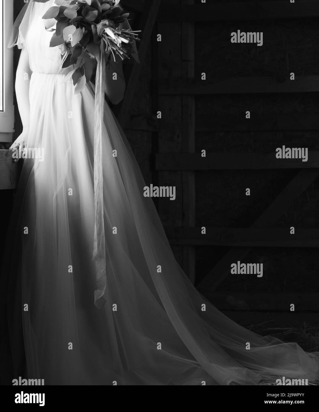 Bride in wedding dress wooden barn waiting at the window. Black and ...