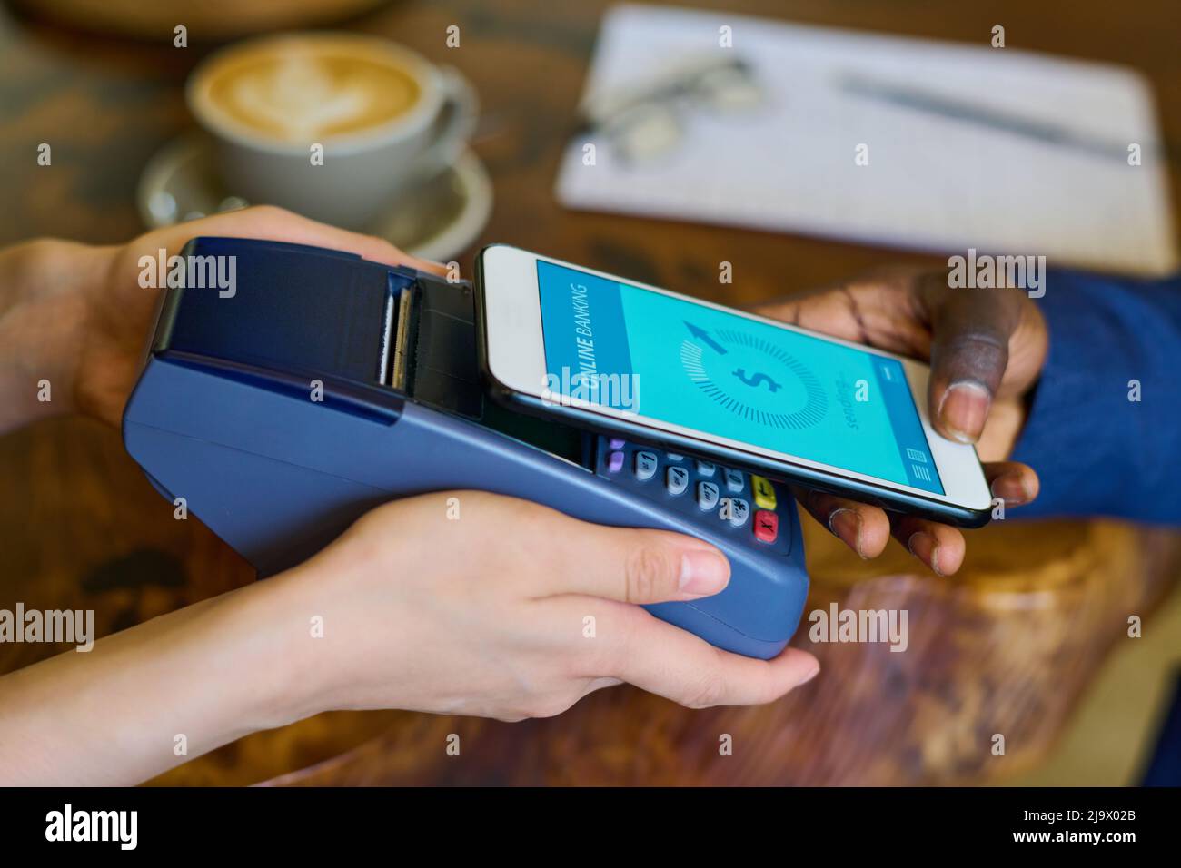 Close-up of customer paying with his mobile phone online while cashier ...
