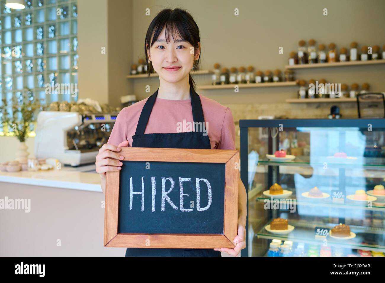 Portrait of young ASian waitress holding board with hired sign and ...