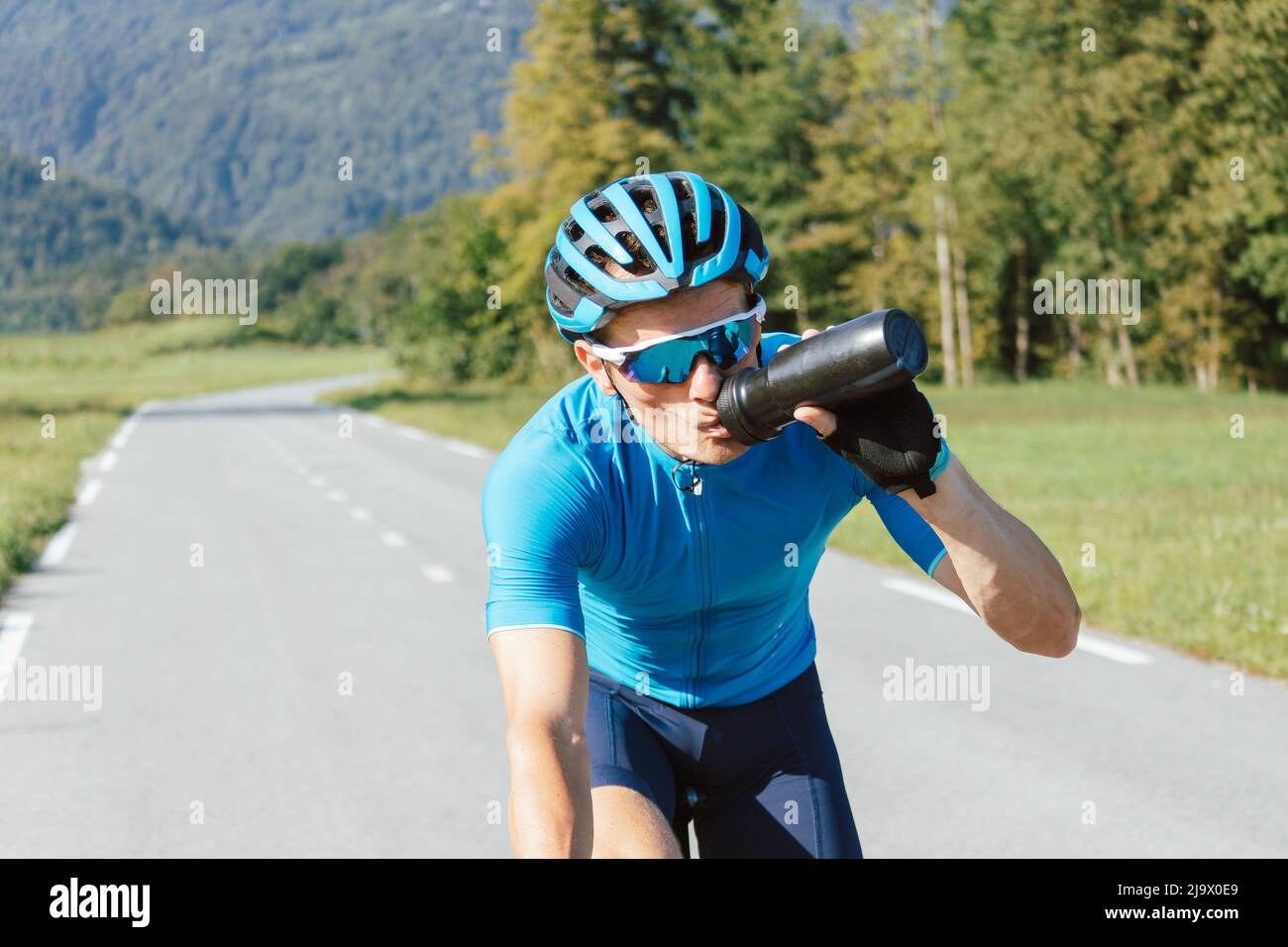 Male cyclist drinking water from bottle during high-intensity pedaling ...