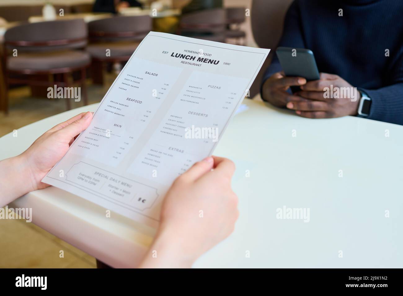 Close-up of unrecognizable woman reading menu while sitting at table ...