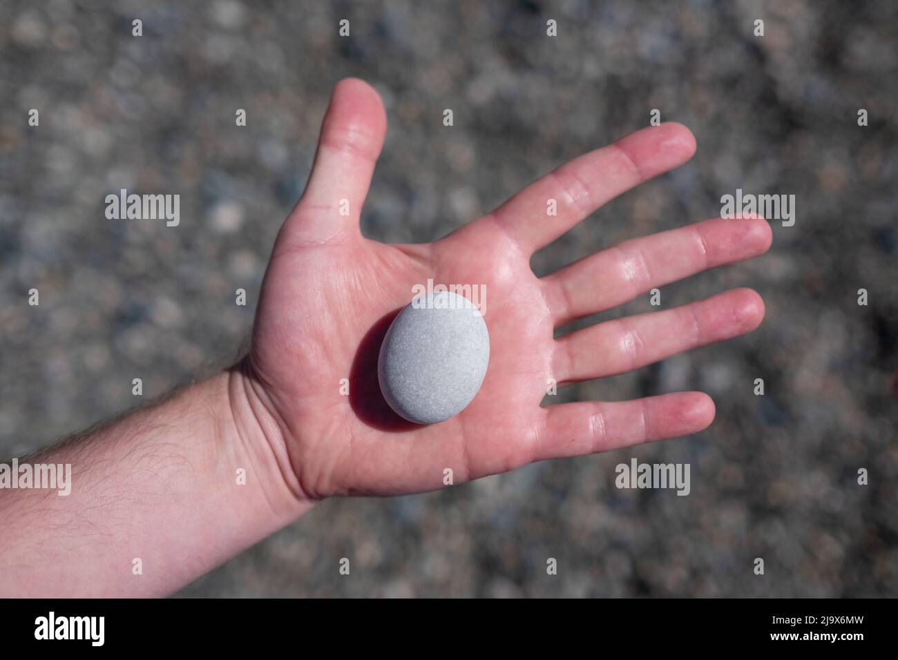Man holding round stone in hand resting on the seaside during vacation ...