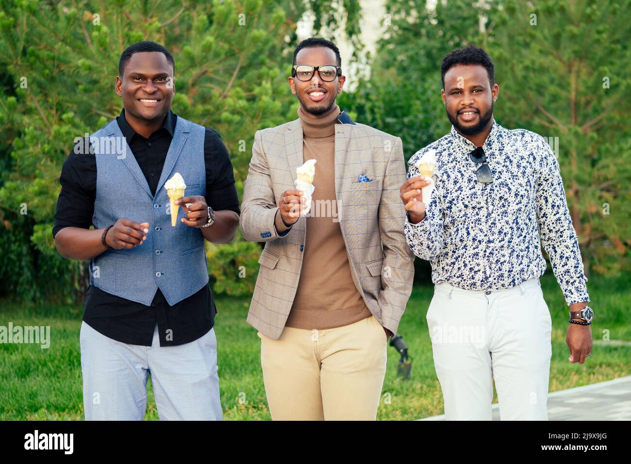 a group of three black men in stylish suits a meeting in a summer park ...