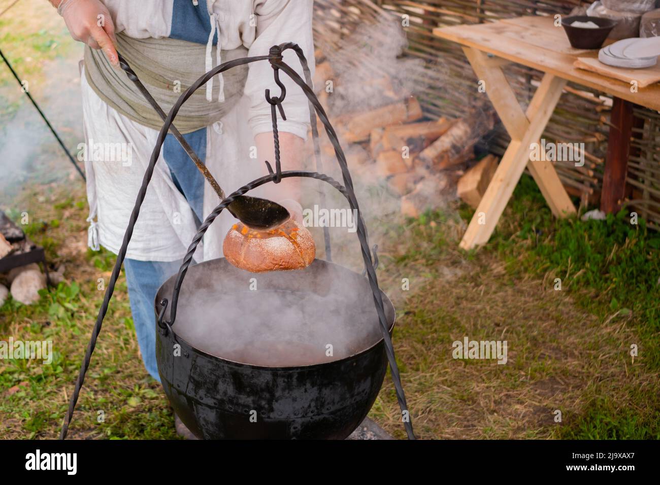 Preparing soup in hanging pot over open fire - camping concept Stock ...