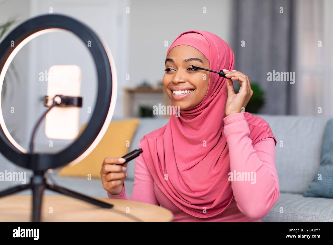 Online makeup lesson from beauty blogger. Happy black lady applying ...